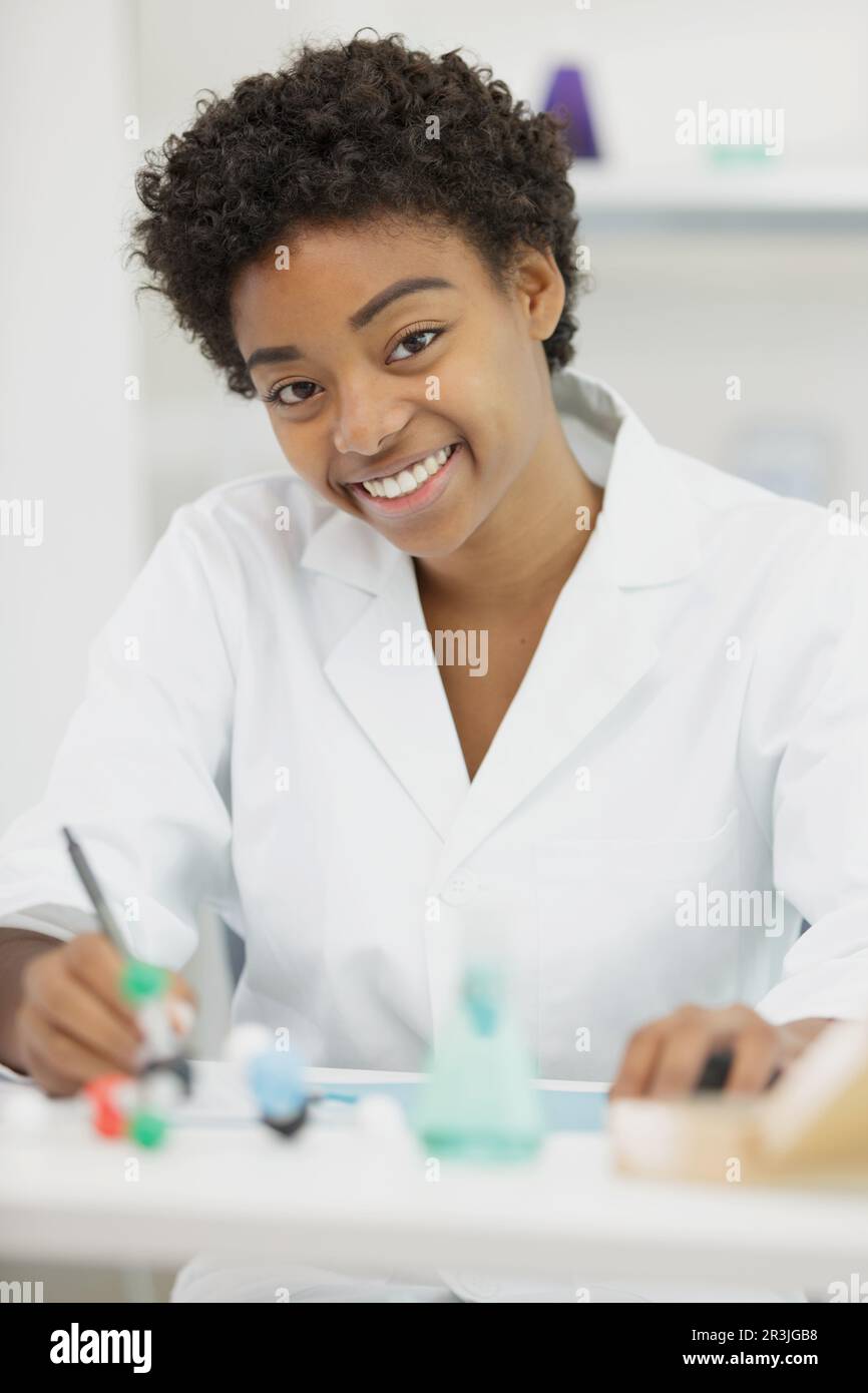 smiling chemist wearing coat sitting in lab Stock Photo - Alamy