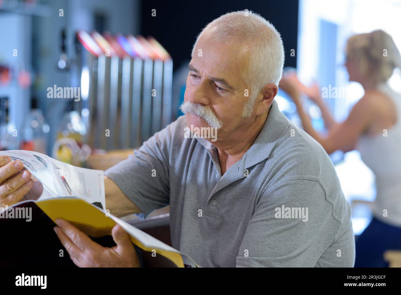 elderly man reading magazine in a bistro Stock Photo - Alamy