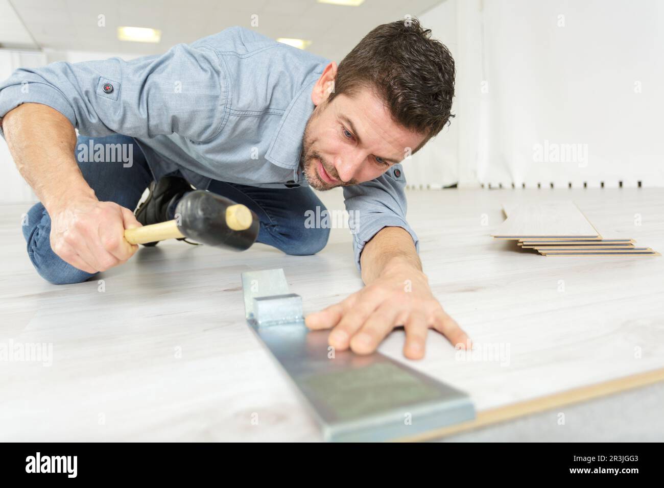 handsome man measuring wooden flooring with hammer Stock Photo - Alamy