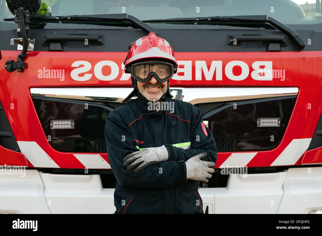 Firefighter posing in front of a fire truck with his arms crossed. High quality photography ...