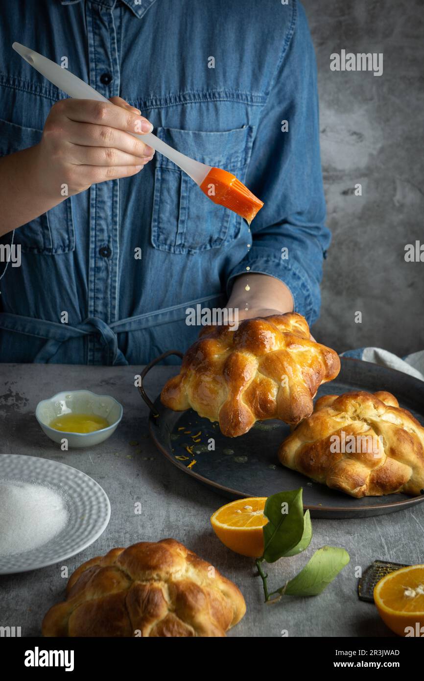 Woman preparing Pan de muertos bread of the dead for Mexican day of the ...