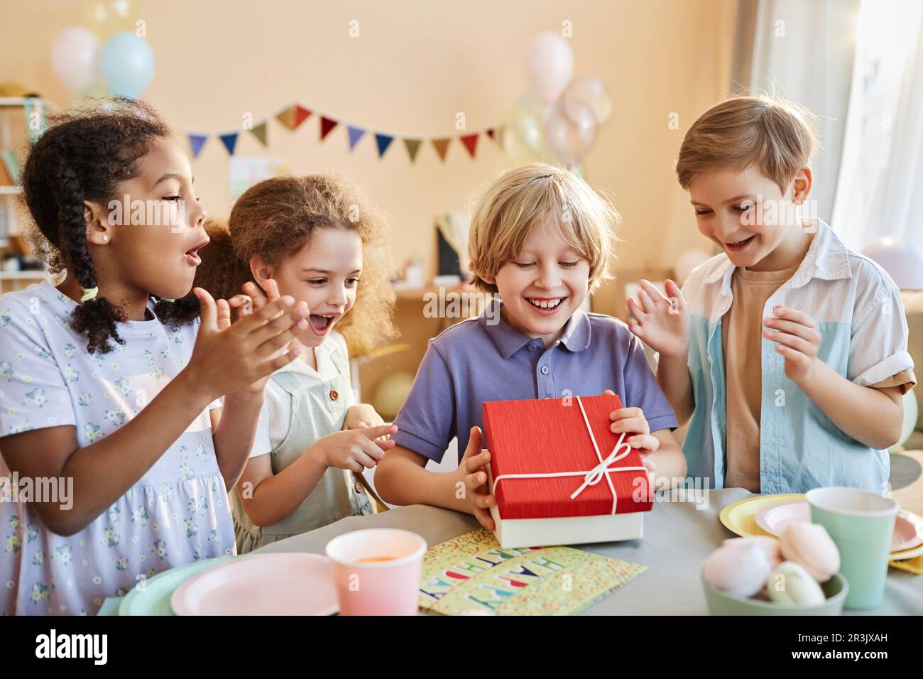 Diverse group of happy children at Birthday party with excited boy ...