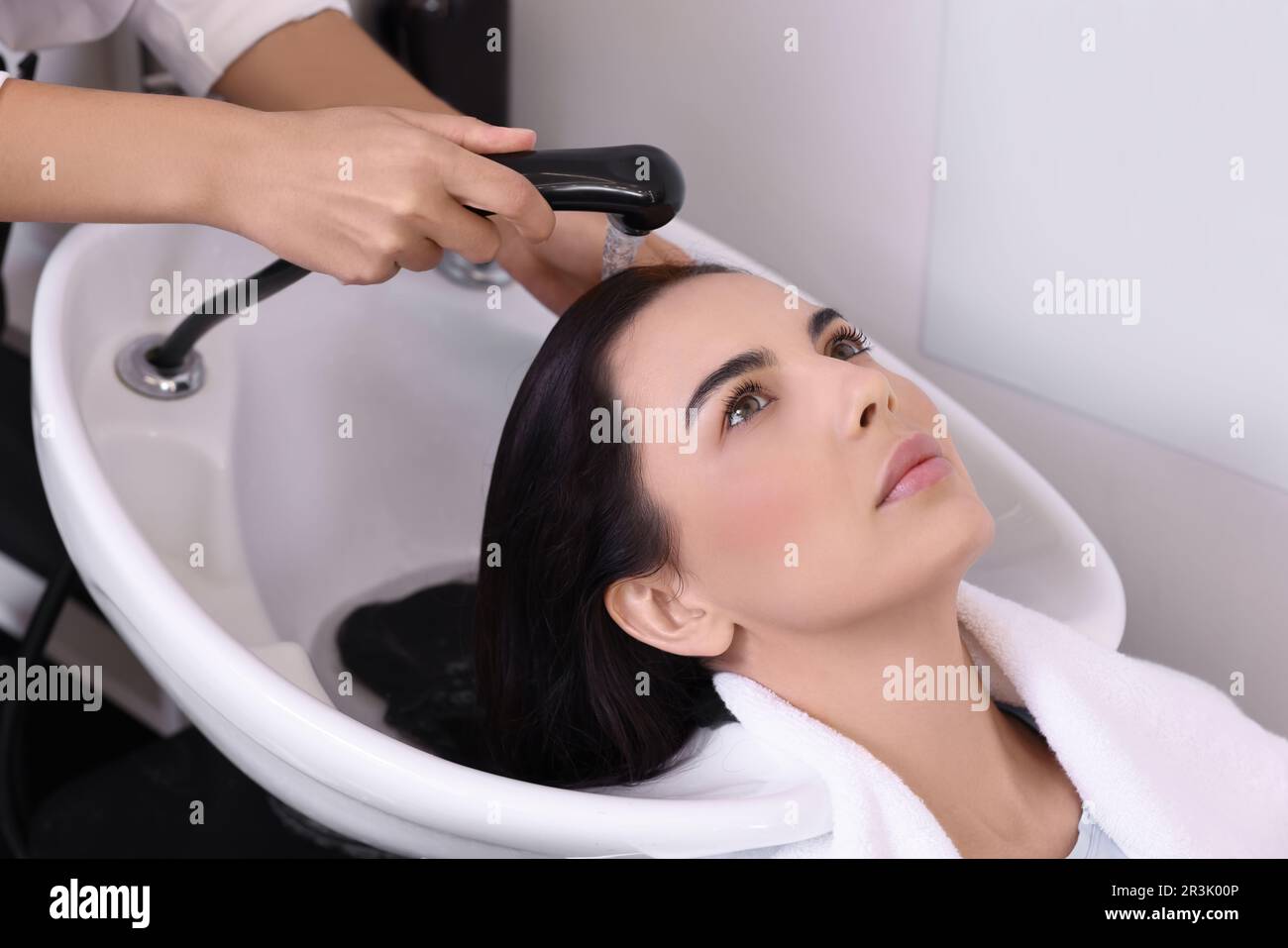 Professional hairdresser washing woman's hair in beauty salon, closeup ...