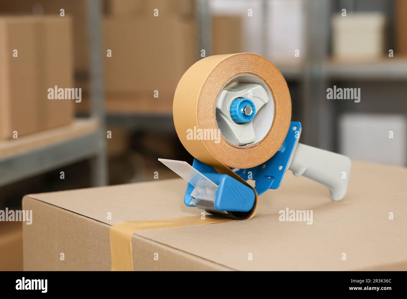 Taping cardboard box with adhesive tape dispenser indoors Stock Photo ...
