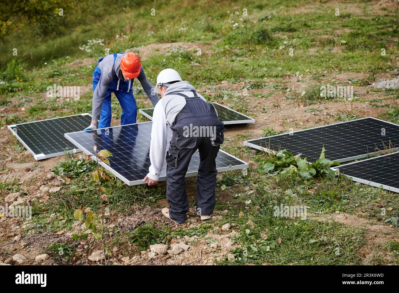 Workers building solar panel system. Men technicians in helmets ...