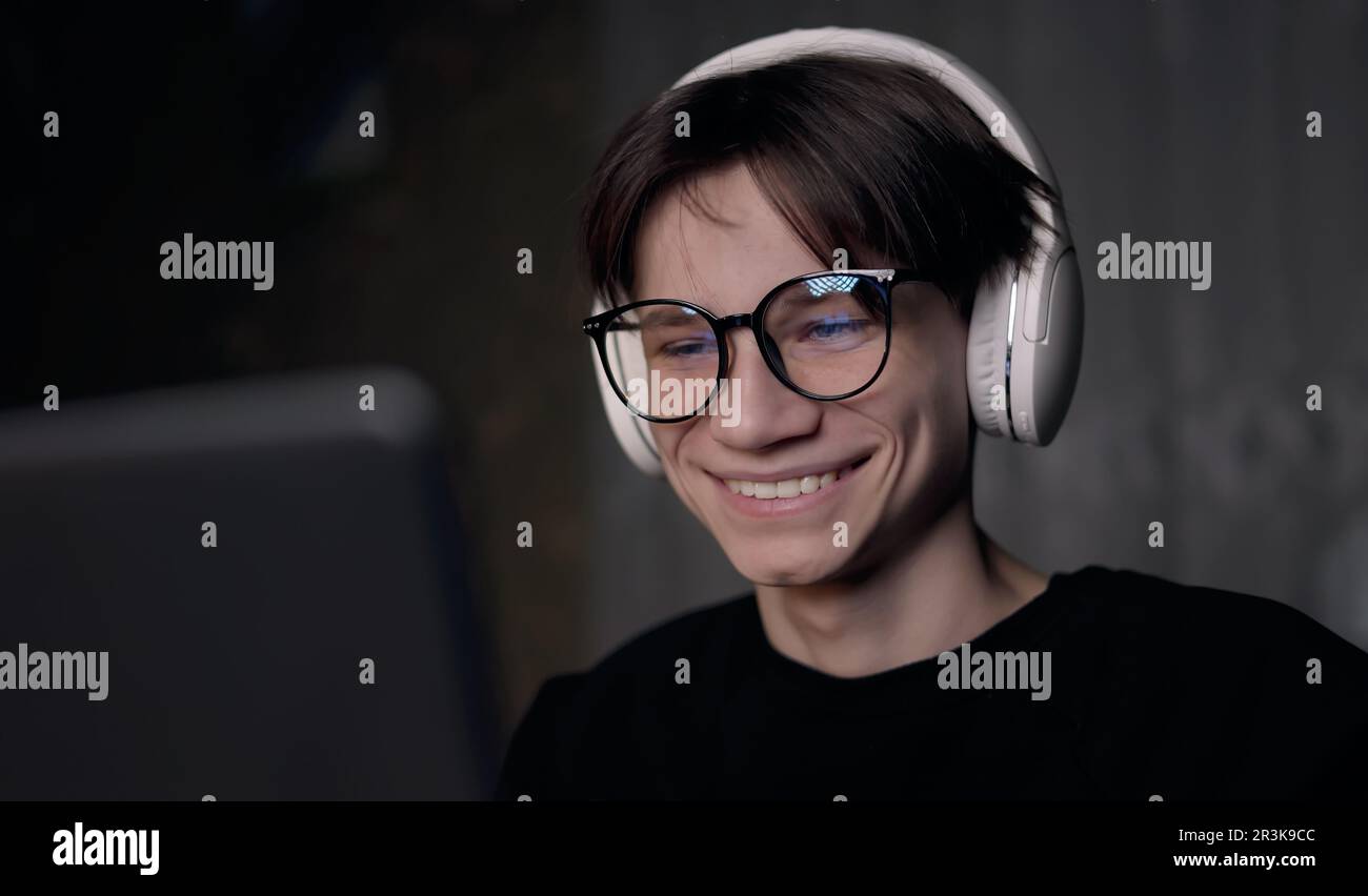 Young gamer man in glasses with screen reflection and headphones ...