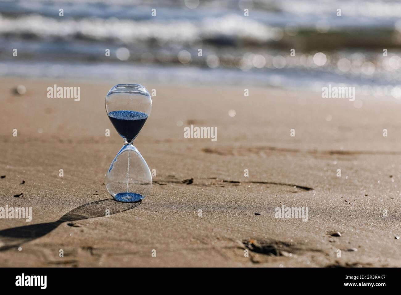 Hourglass with blue sand inside in a warm golden morning sunlight with ...