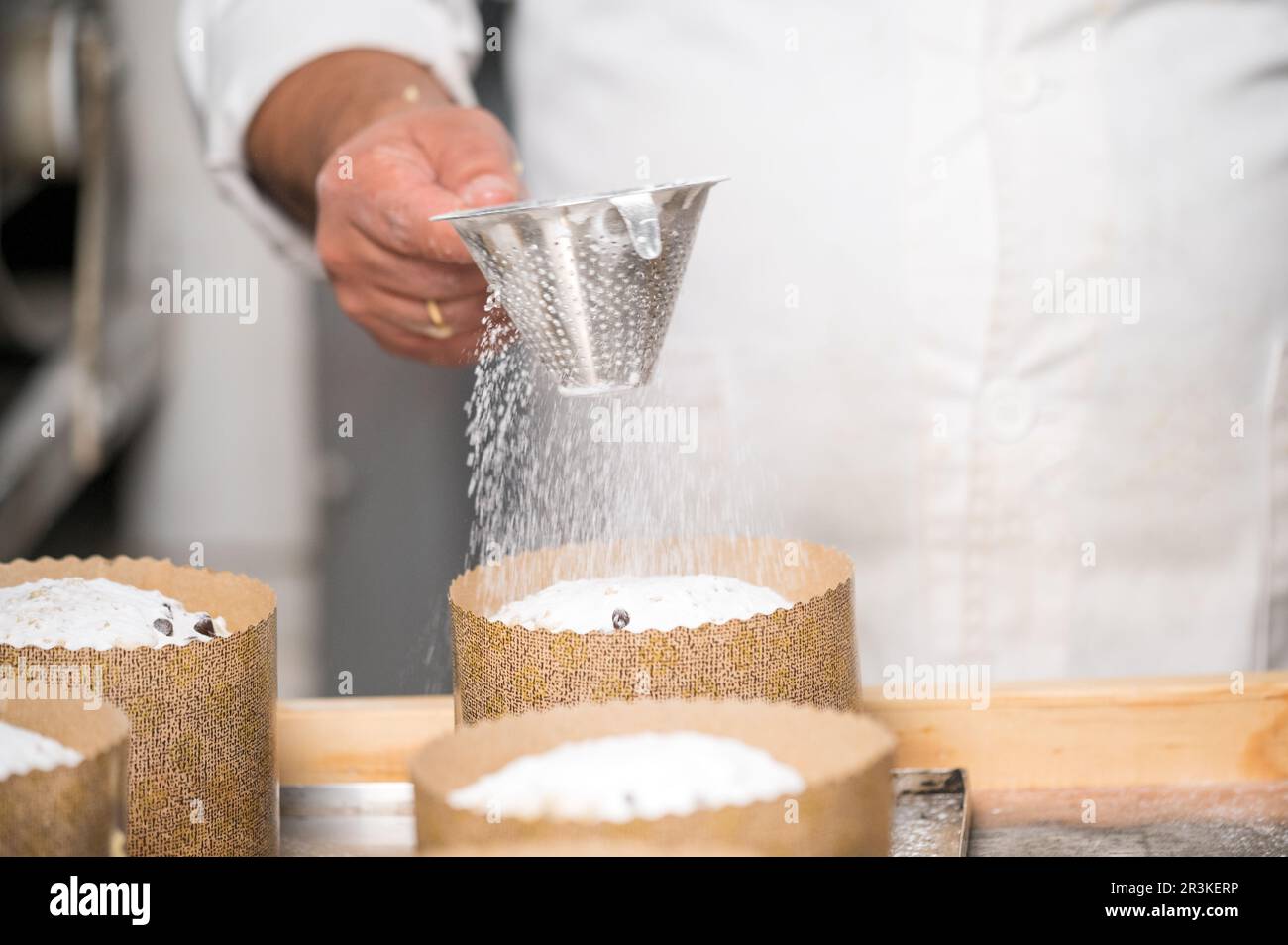 Pastry chef Topping Traditional Italian panettones with powdered sugar ...