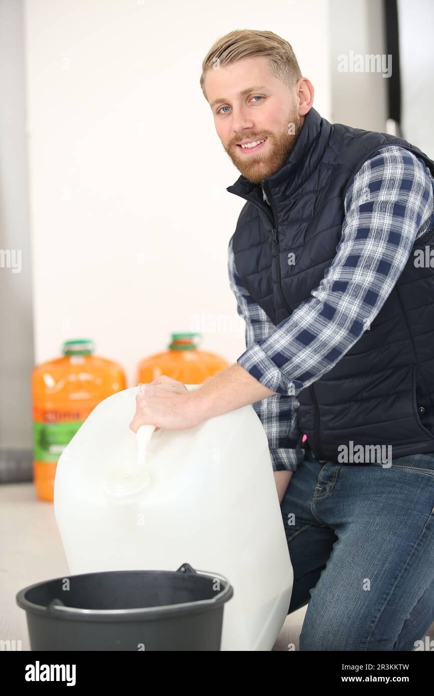 man pouring from industrial plastic container into a bucket Stock Photo ...