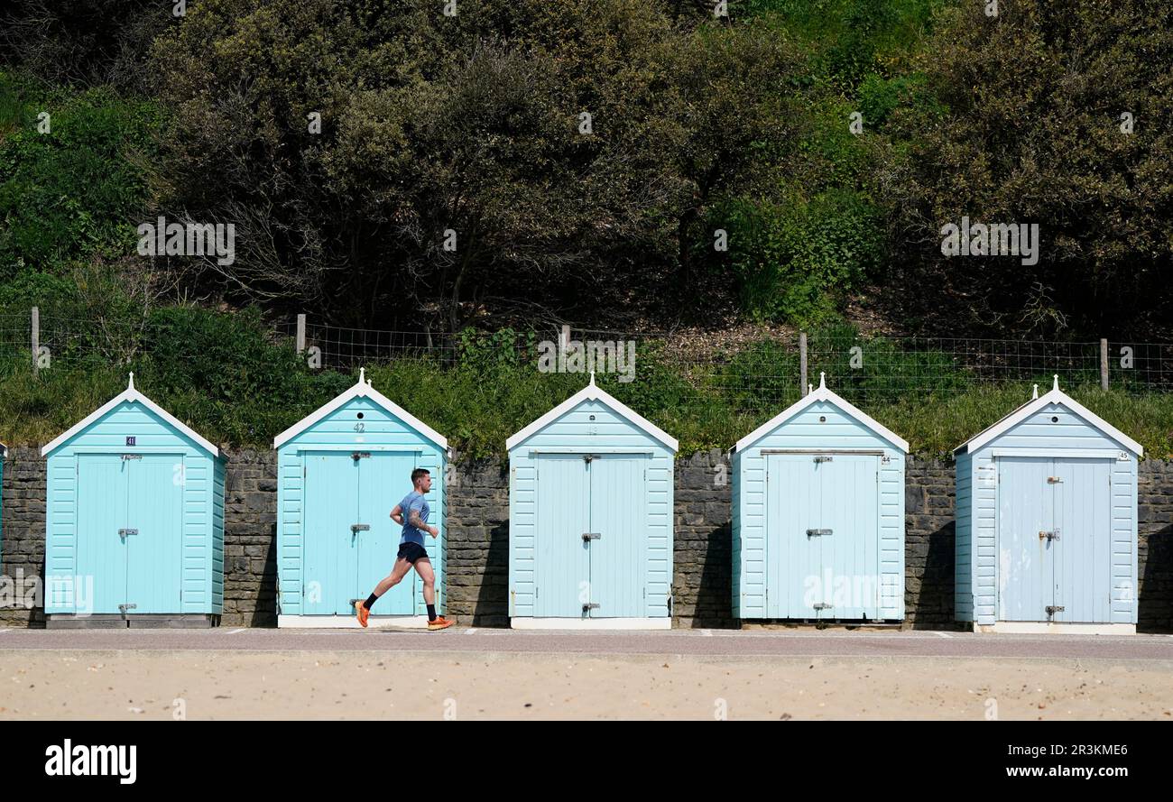 People make their way past beach huts on Bournemouth beach in Dorset ...