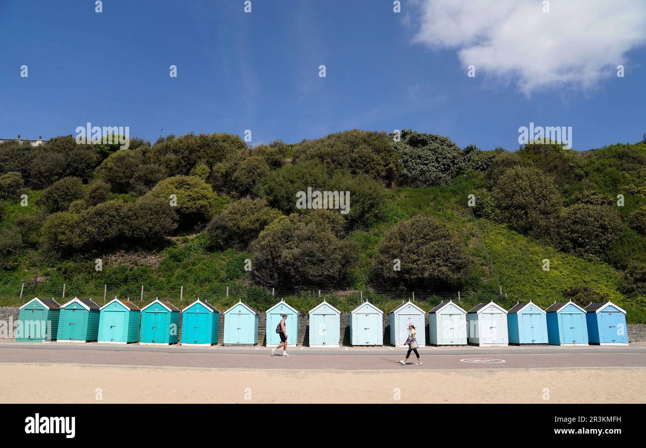 People make their way past beach huts on Bournemouth beach in Dorset ...