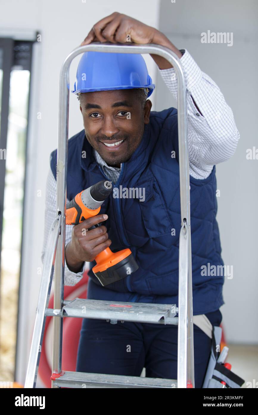 Construction worker is standing and holding a ladder hi-res stock ...