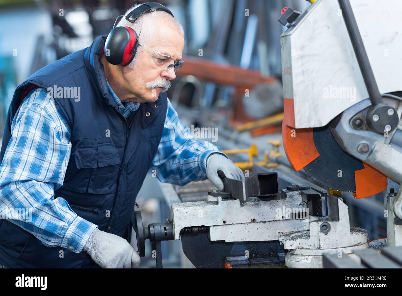 elderly worker watches processing of detail on milling machine Stock ...