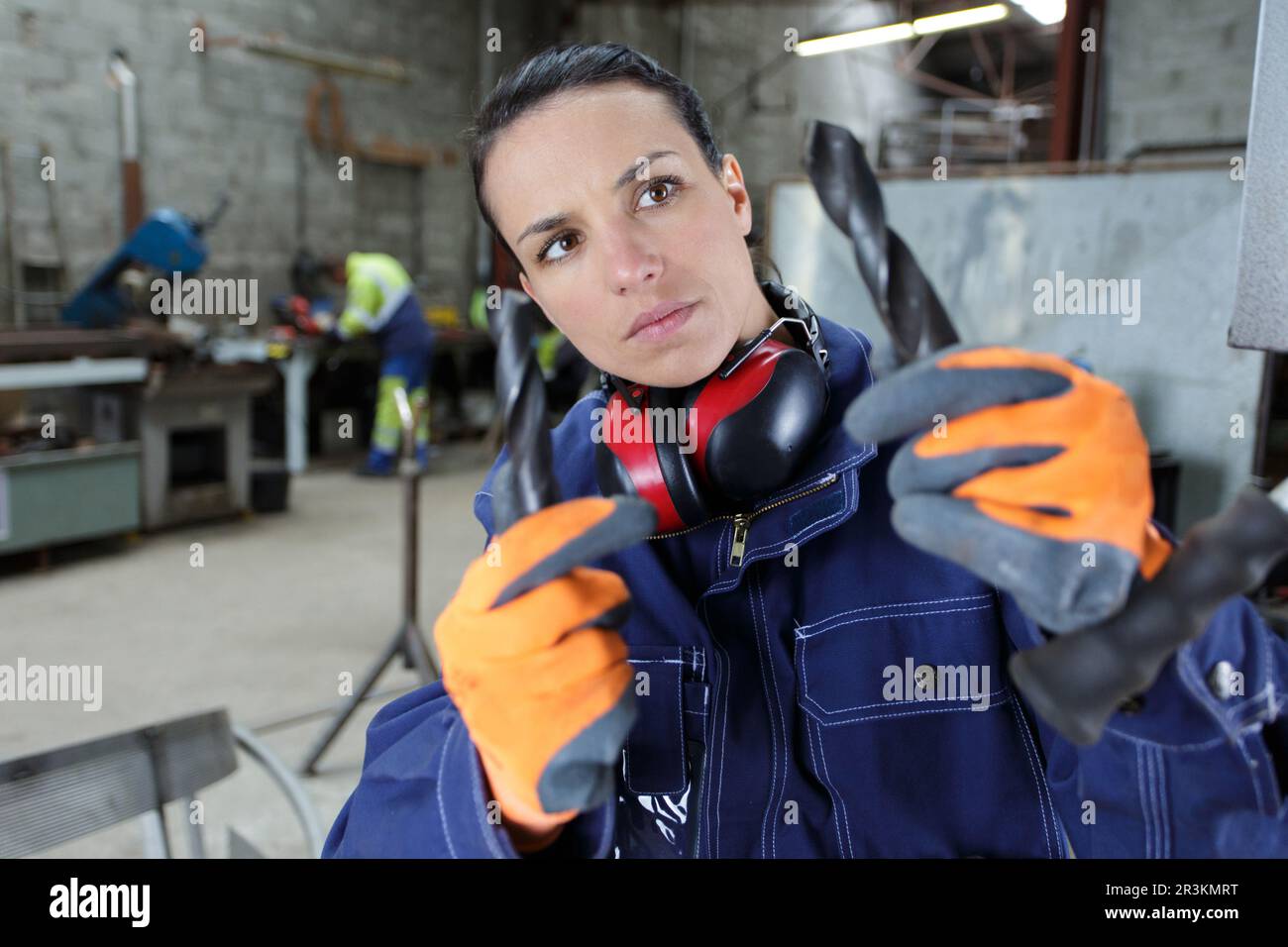 female worker comparing two metal drill bits Stock Photo - Alamy