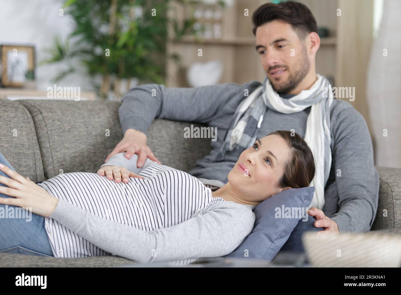 pregant woman and husband lying on couch toucher her belly Stock Photo ...