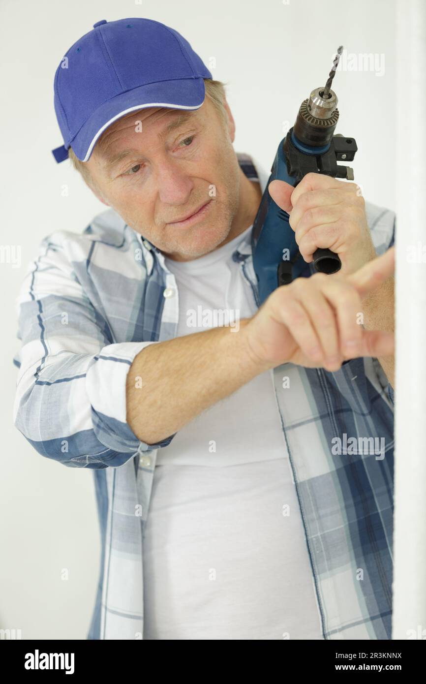 senior man doing housework holding drill Stock Photo - Alamy