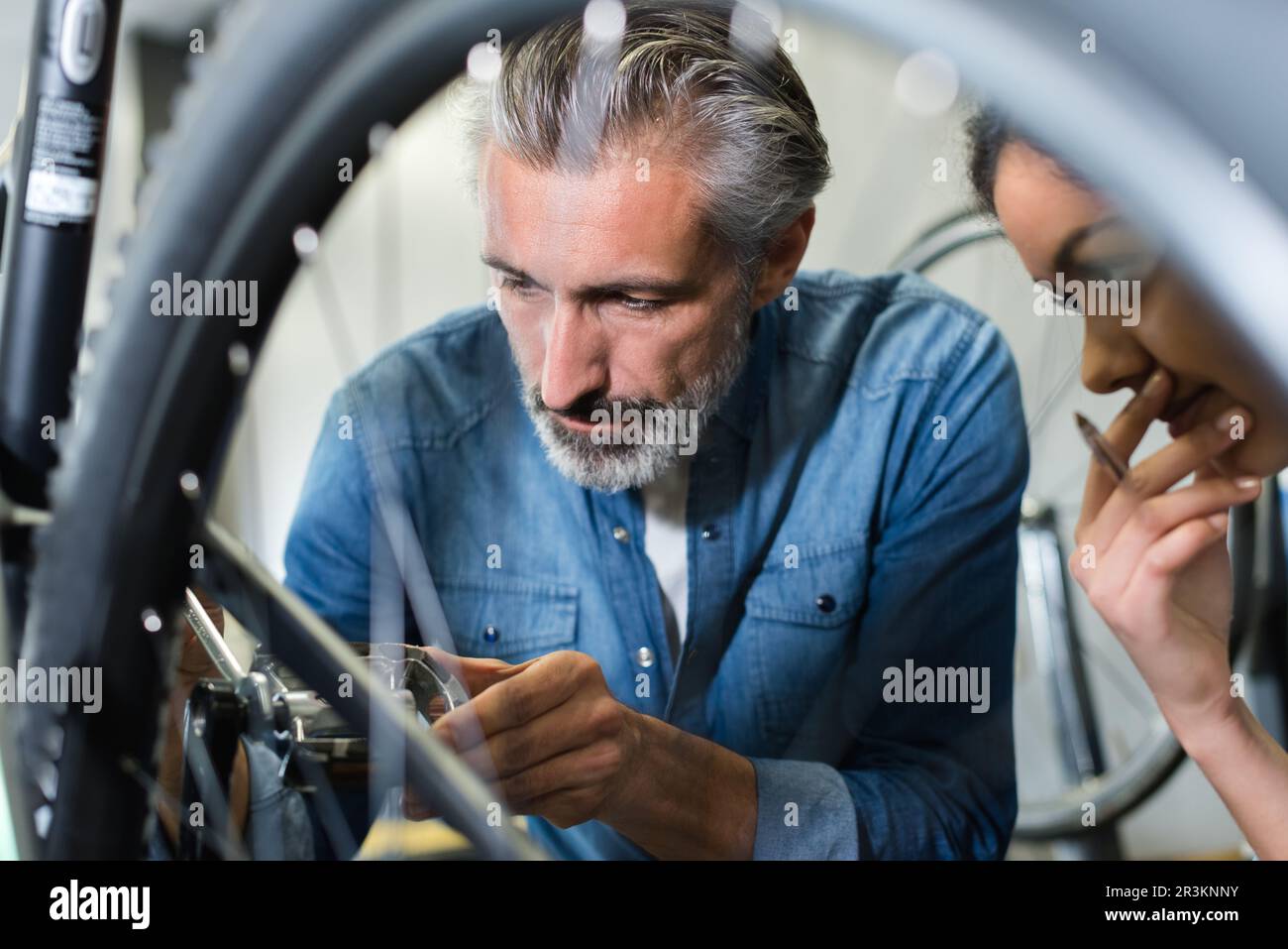 senior mechanic working on bicycle woman watching Stock Photo - Alamy
