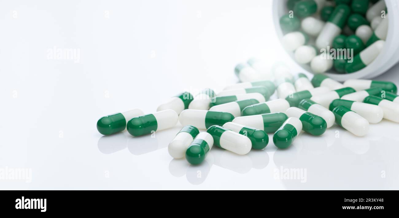 Green and white capsule pill spread out of pill bottle. Healthcare and ...