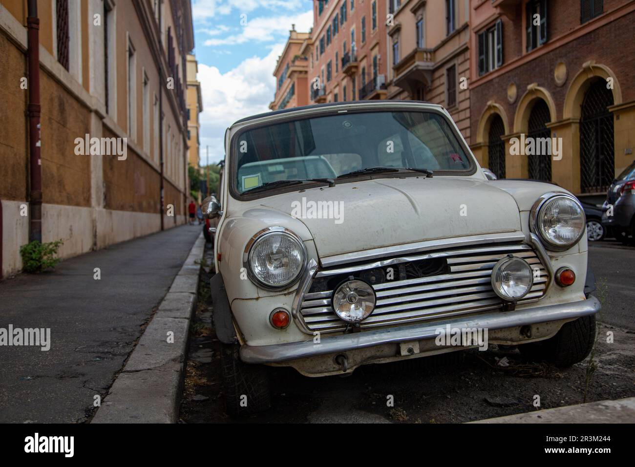 A white old vintage car with round headlights on the bumper, street of ...