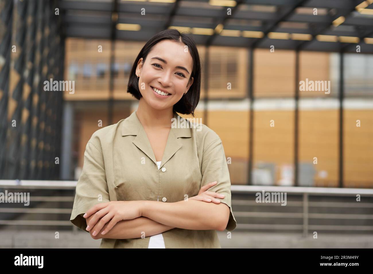 Portrait of young asian woman standing with confidence, cross arms on ...