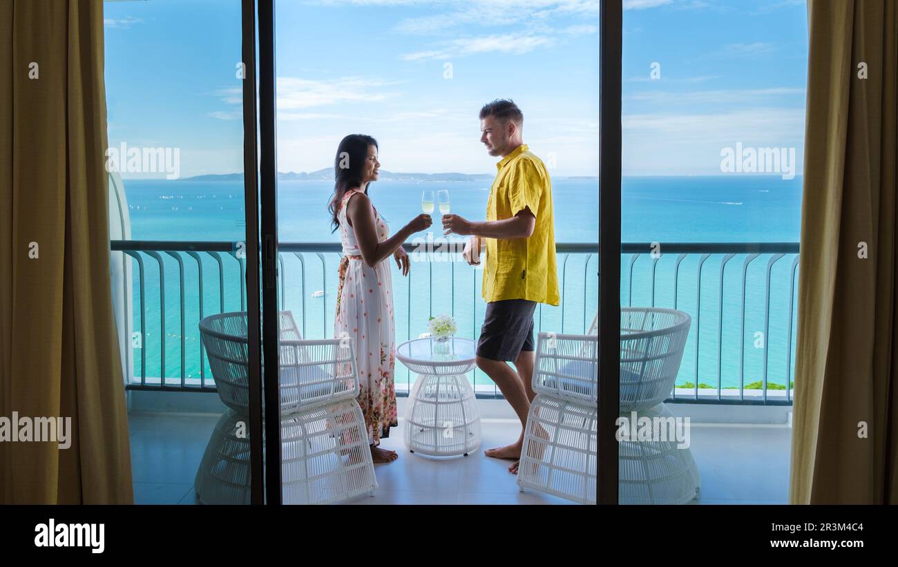 Couple of men and women drinking cocktails at balcony of a hotel in ...
