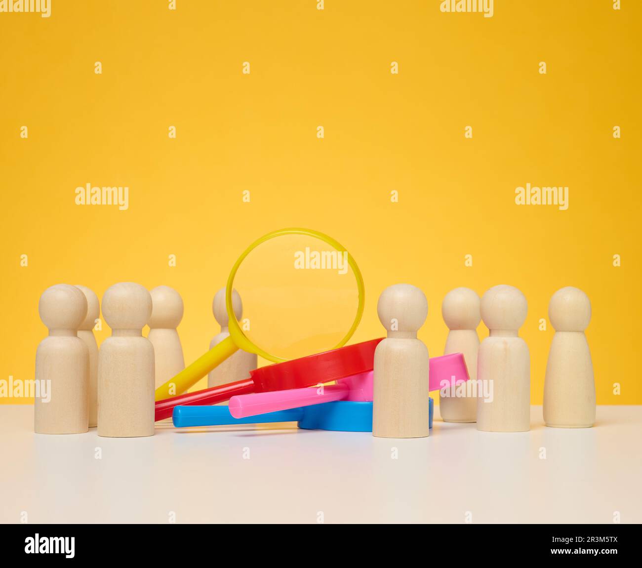 Wooden figures of men stand on a yellow background and a plastic ...