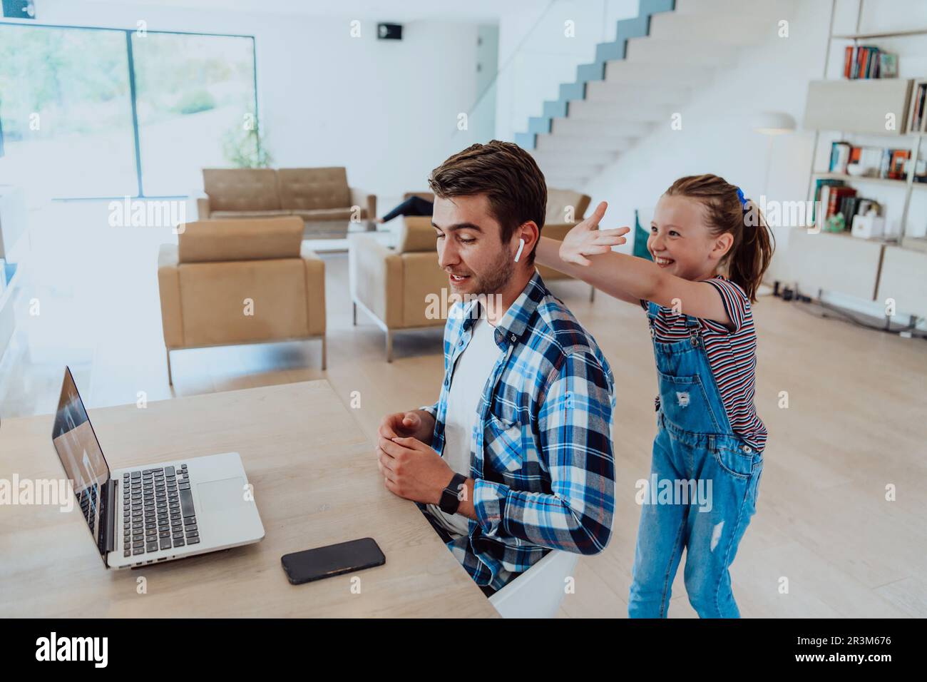 Work from home. Daughter interrupting her father while he is having a ...