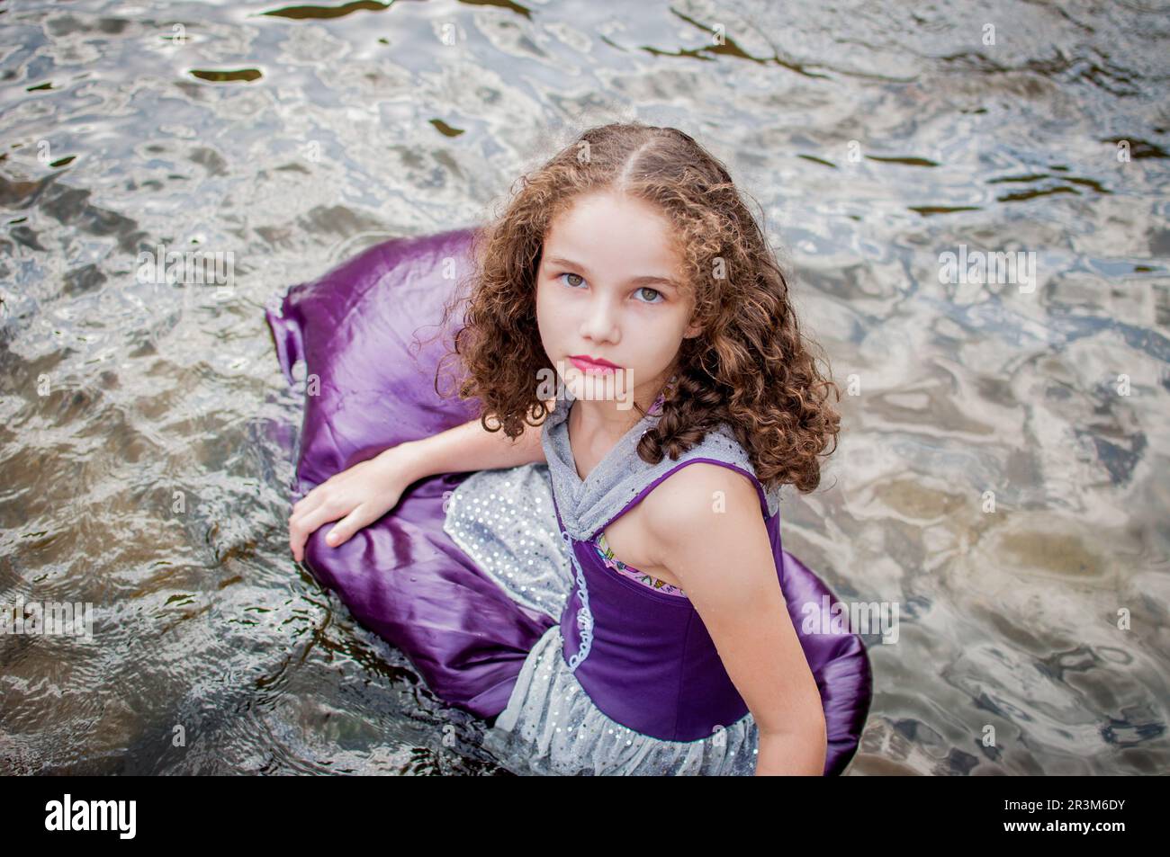 Portrait of a beautiful girl posing inside the river wearing a princess ...