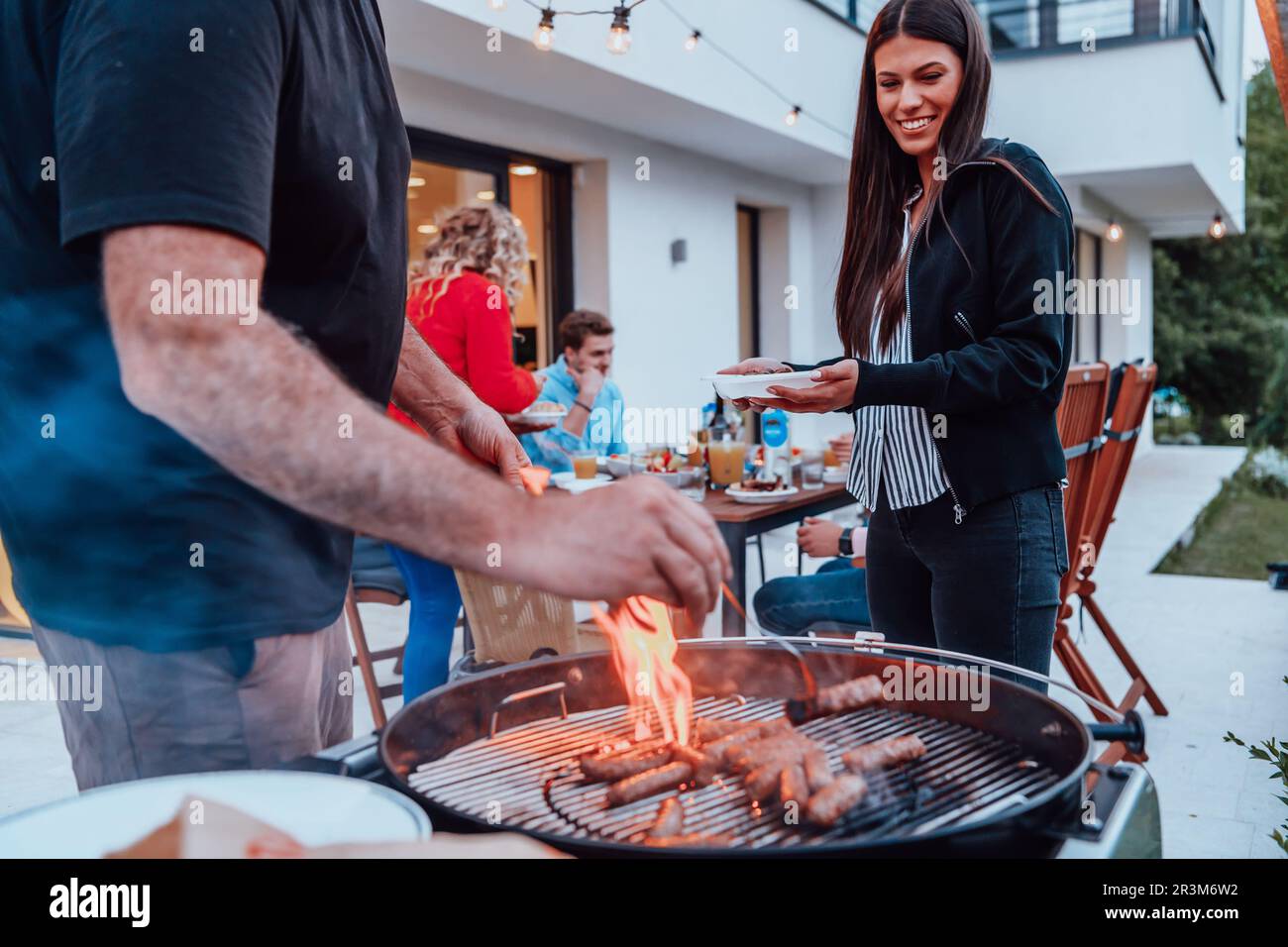 A group of friends and family barbecue together in the evening on the ...