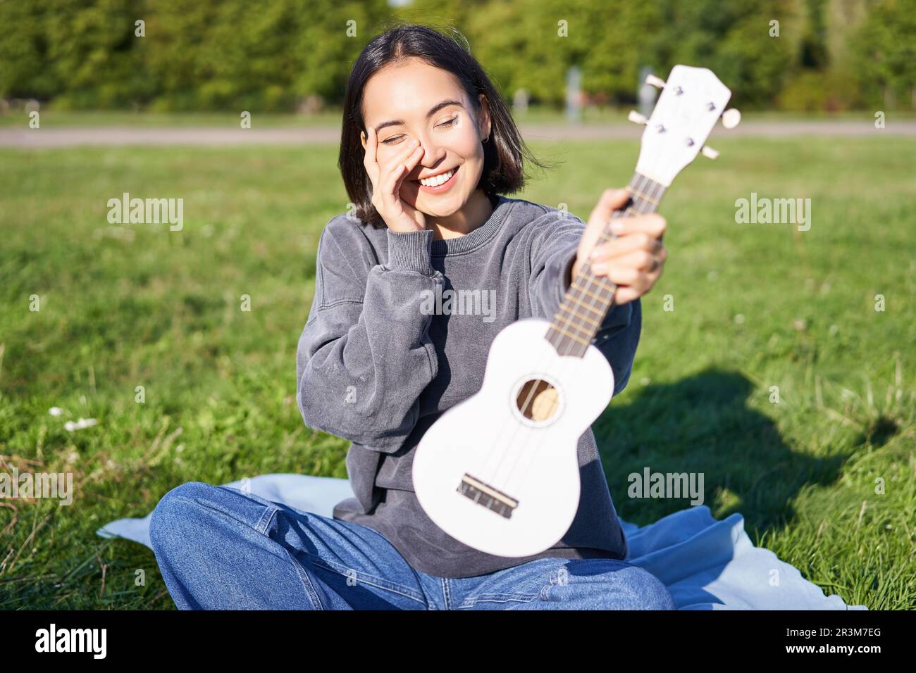 Beautiful Asian Girl With Happy Smile Shows Her Ukulele Sits Outside