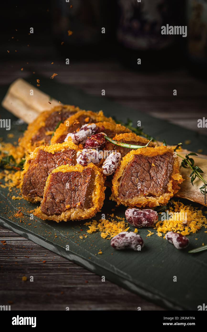 Smoked beef ribs with bone and barbecue sauce on a white square plate ...