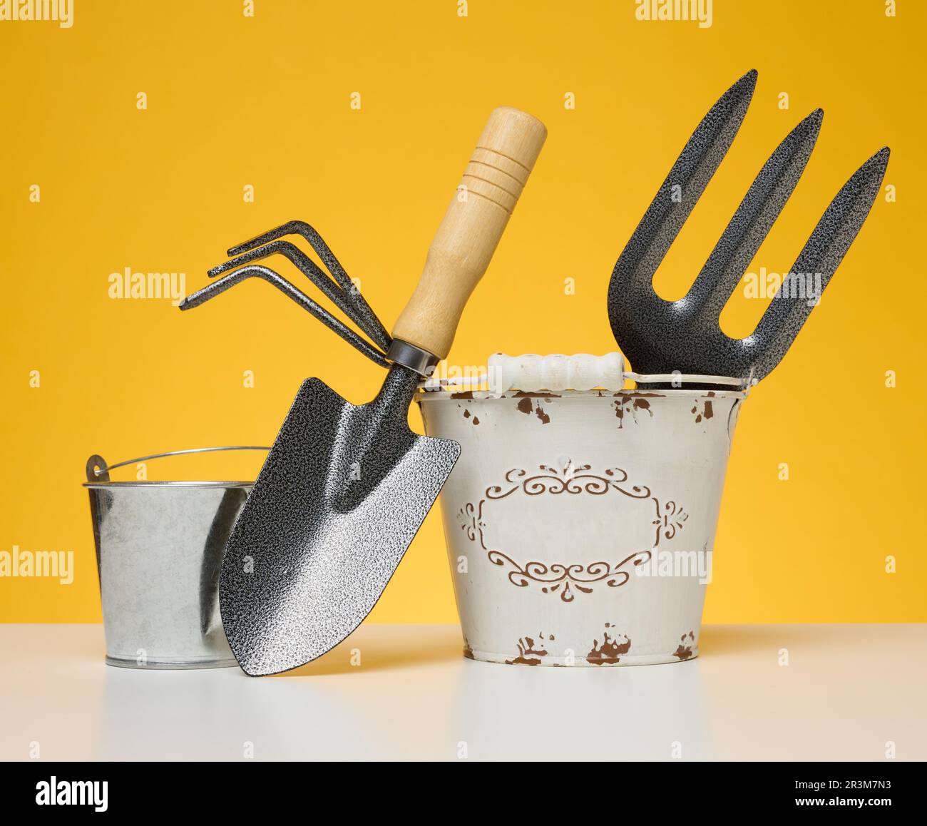 Miniature garden tools in a metal bucket on a yellow background Stock ...