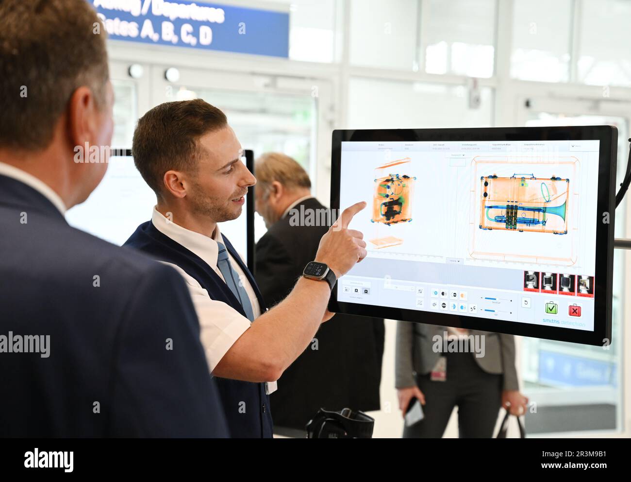 24 May 2023, Bavaria, Munich: A security checkpoint employee (r ...