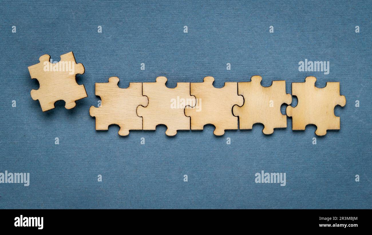row of wooden jigsaw puzzle on blue background, completing a task or ...