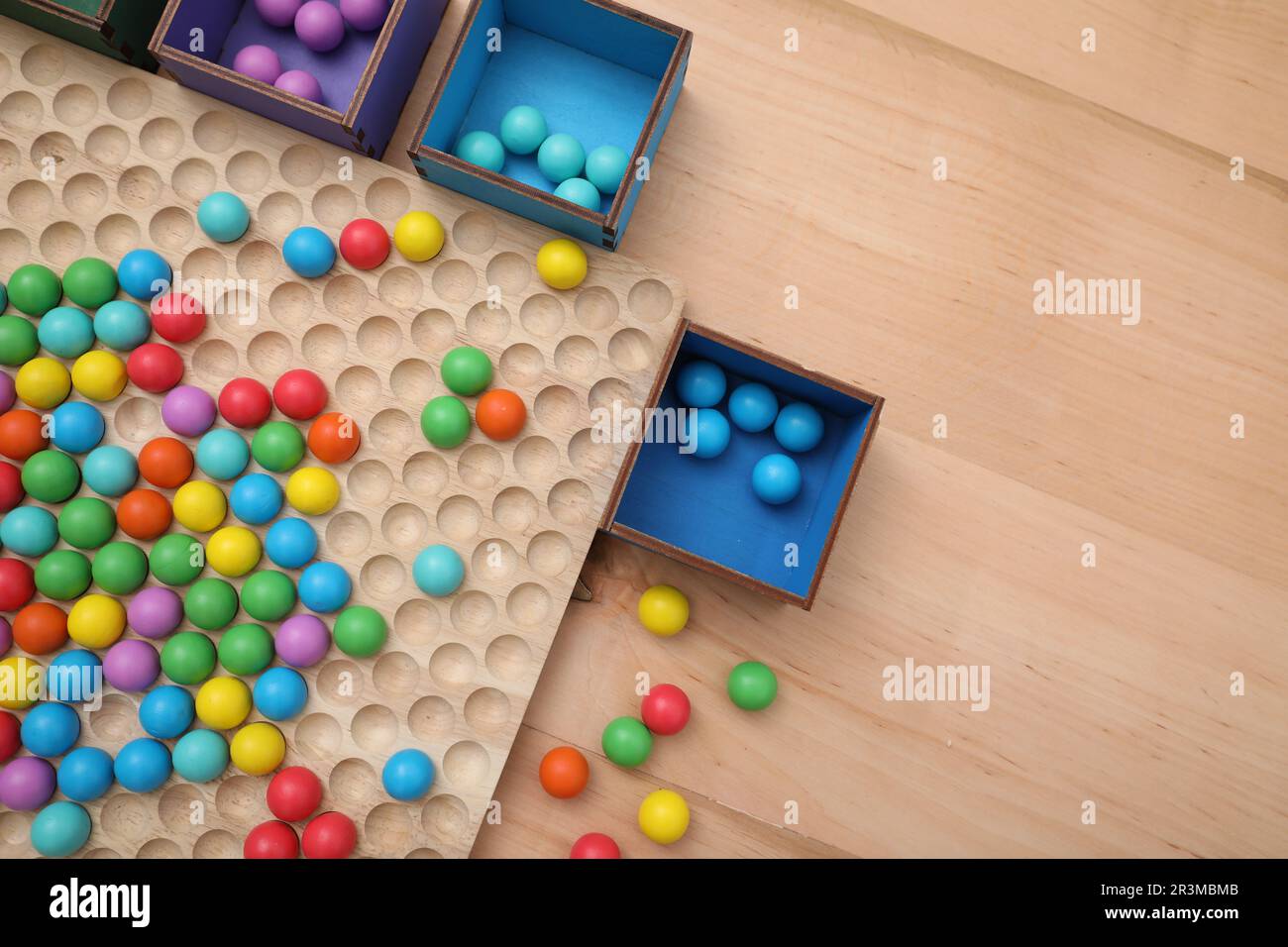 Wooden sorting board and boxes with colorful balls on table, flat lay ...