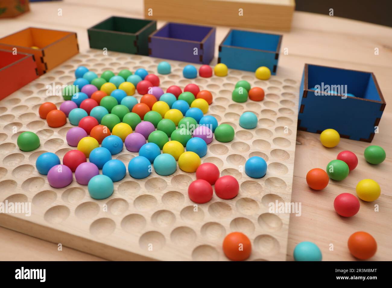 Wooden sorting board and boxes with colorful balls on table, closeup ...