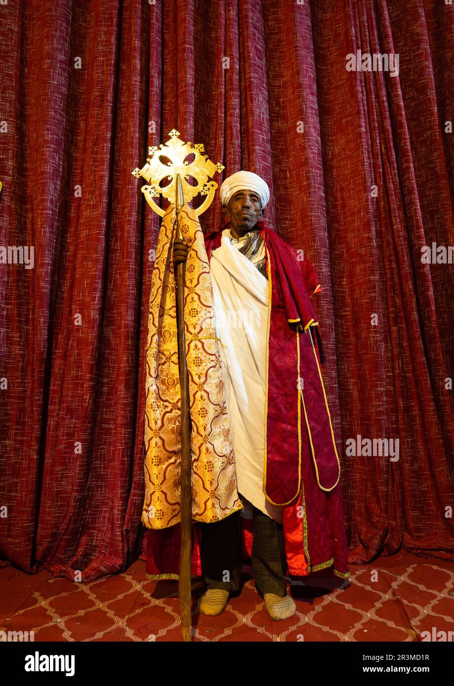 Ethiopian orthodox priest holding a cross inside a rock-hewn church ...
