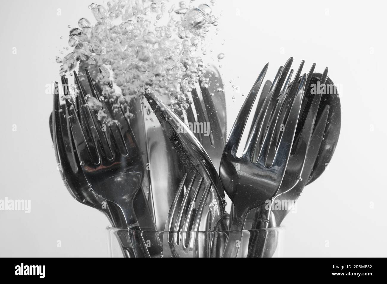 Washing silver cutlery in water on white background Stock Photo - Alamy