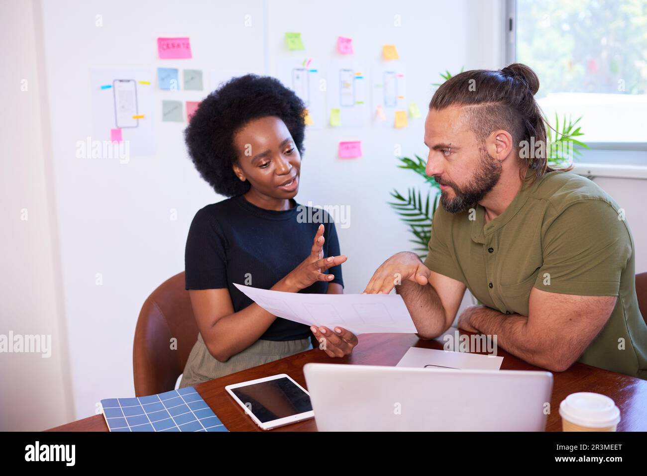 Two team members in a discussion at boardroom table, hand gestures ...
