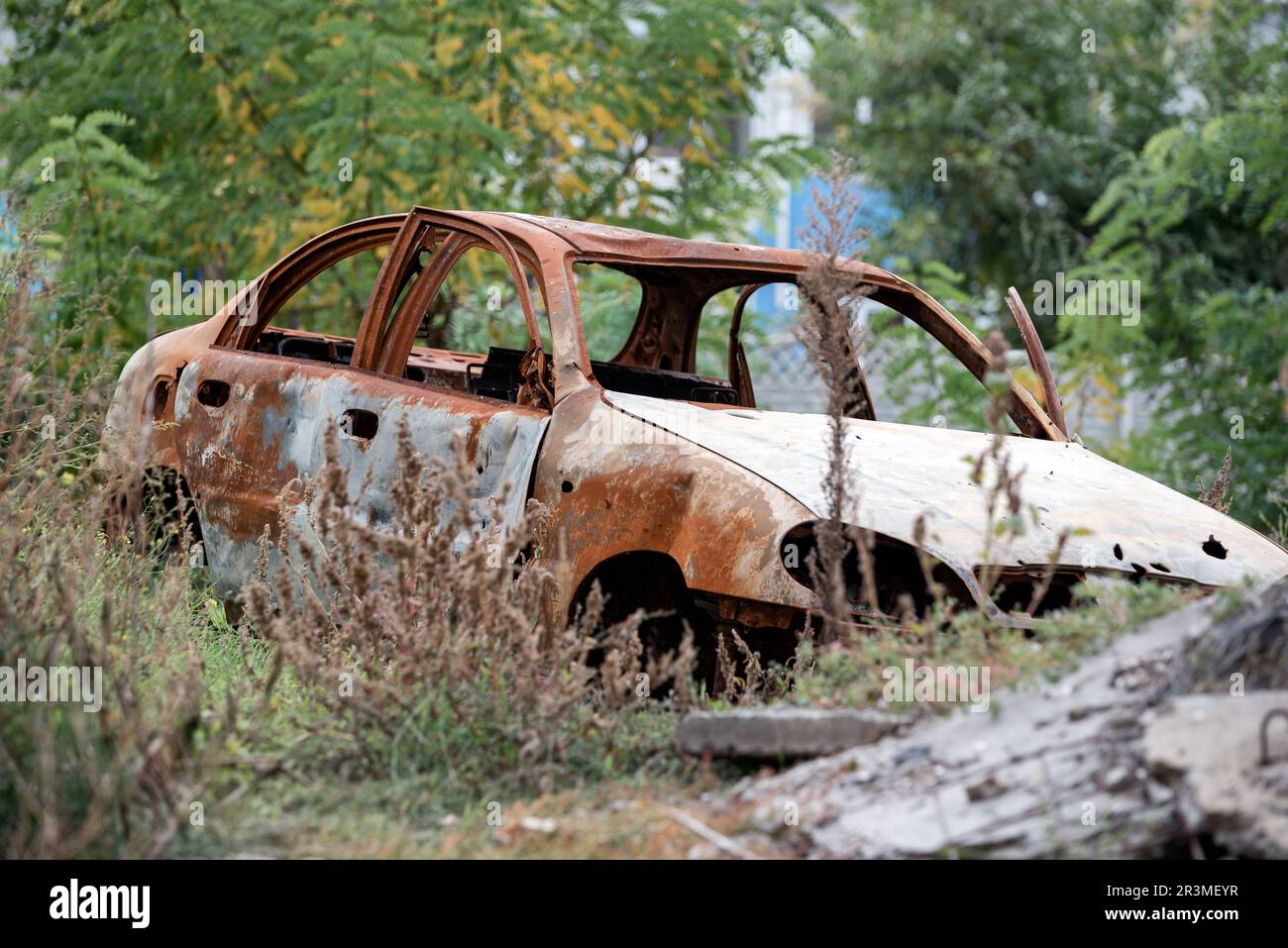 Burned out blown up car against the background of a destroyed house war ...