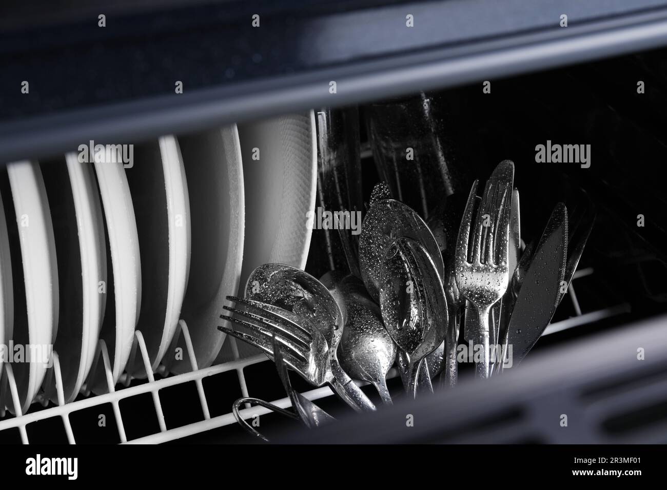 Clean wet plates and cutlery in dishwasher, closeup Stock Photo - Alamy