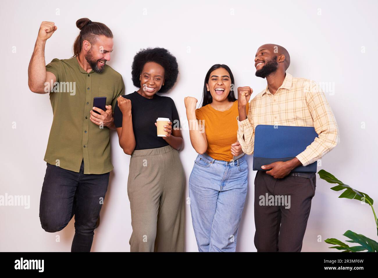 Diverse creative tech team lean against wall and celebrates success ...