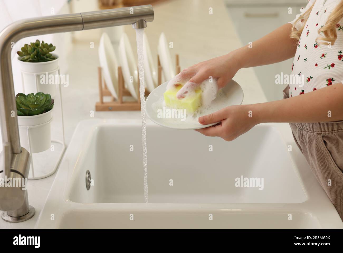 Little girl washing plate above sink in kitchen, closeup Stock Photo ...
