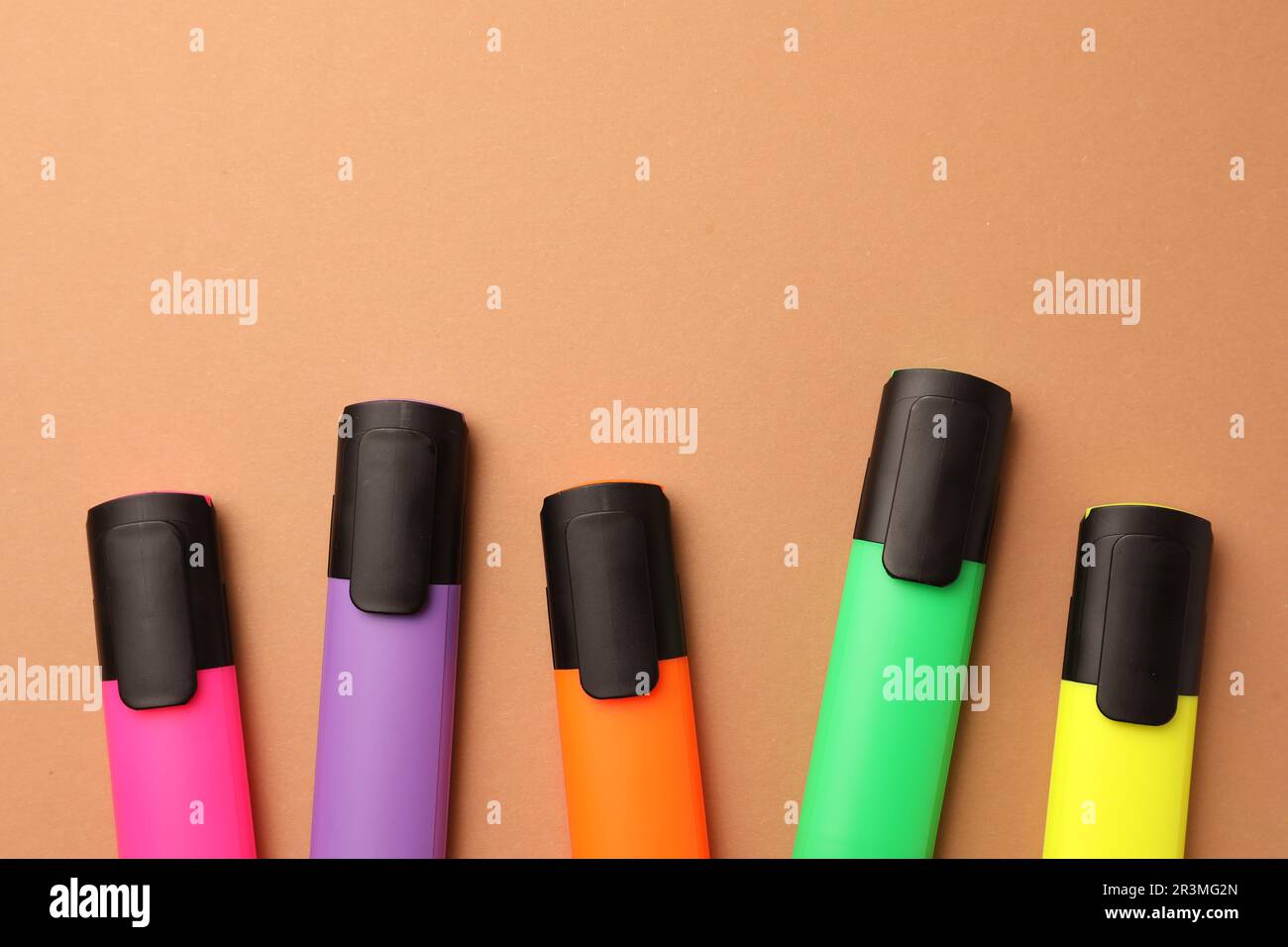 Bright color markers on pale orange background, flat lay. Space for ...