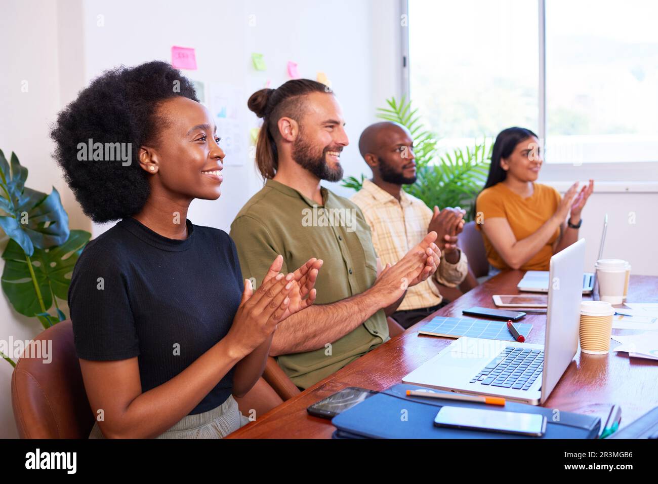 Four diverse team members clapping hands at meeting presentation, tech ...