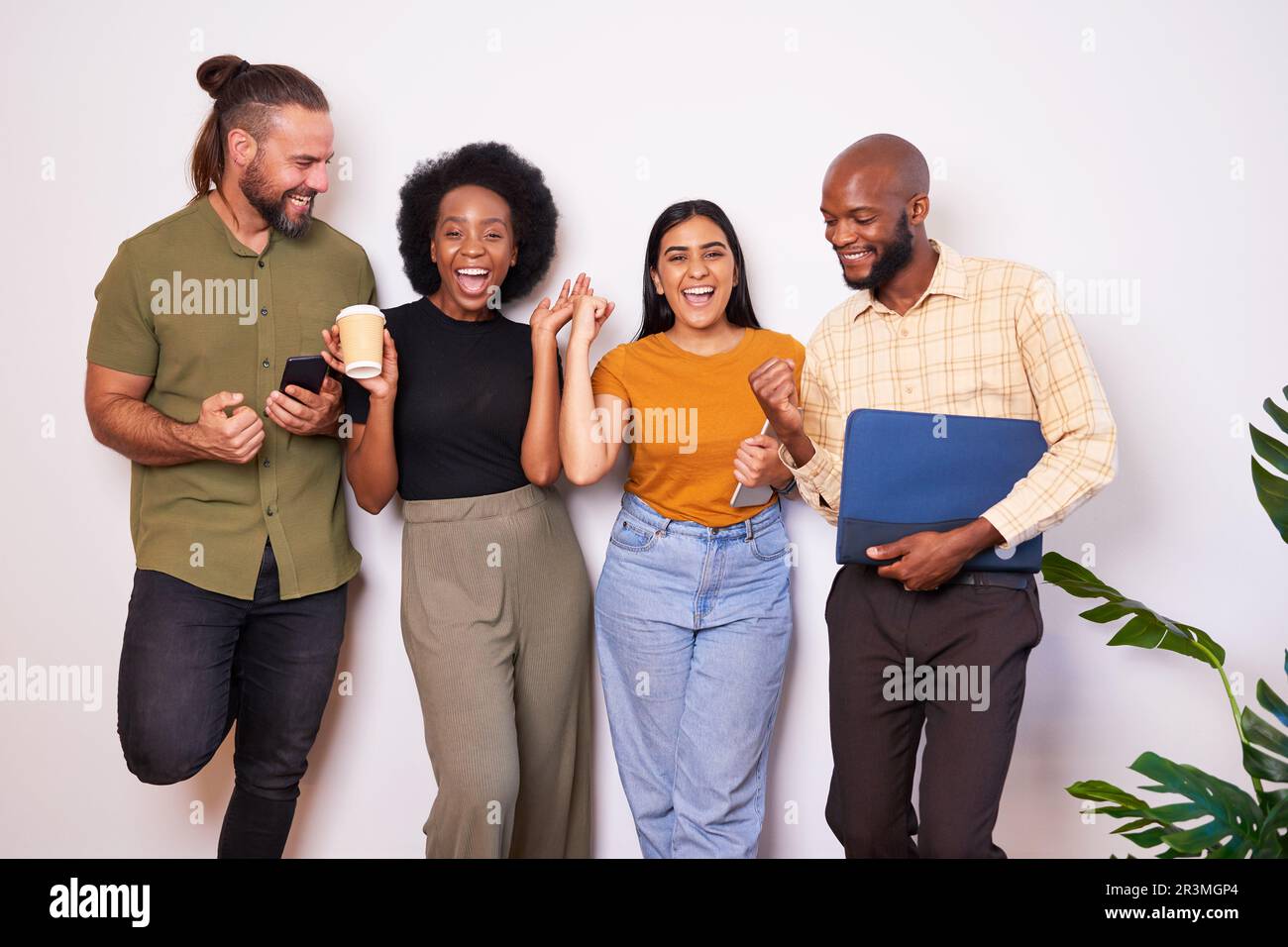 Diverse creative tech team lean against wall and celebrates success ...