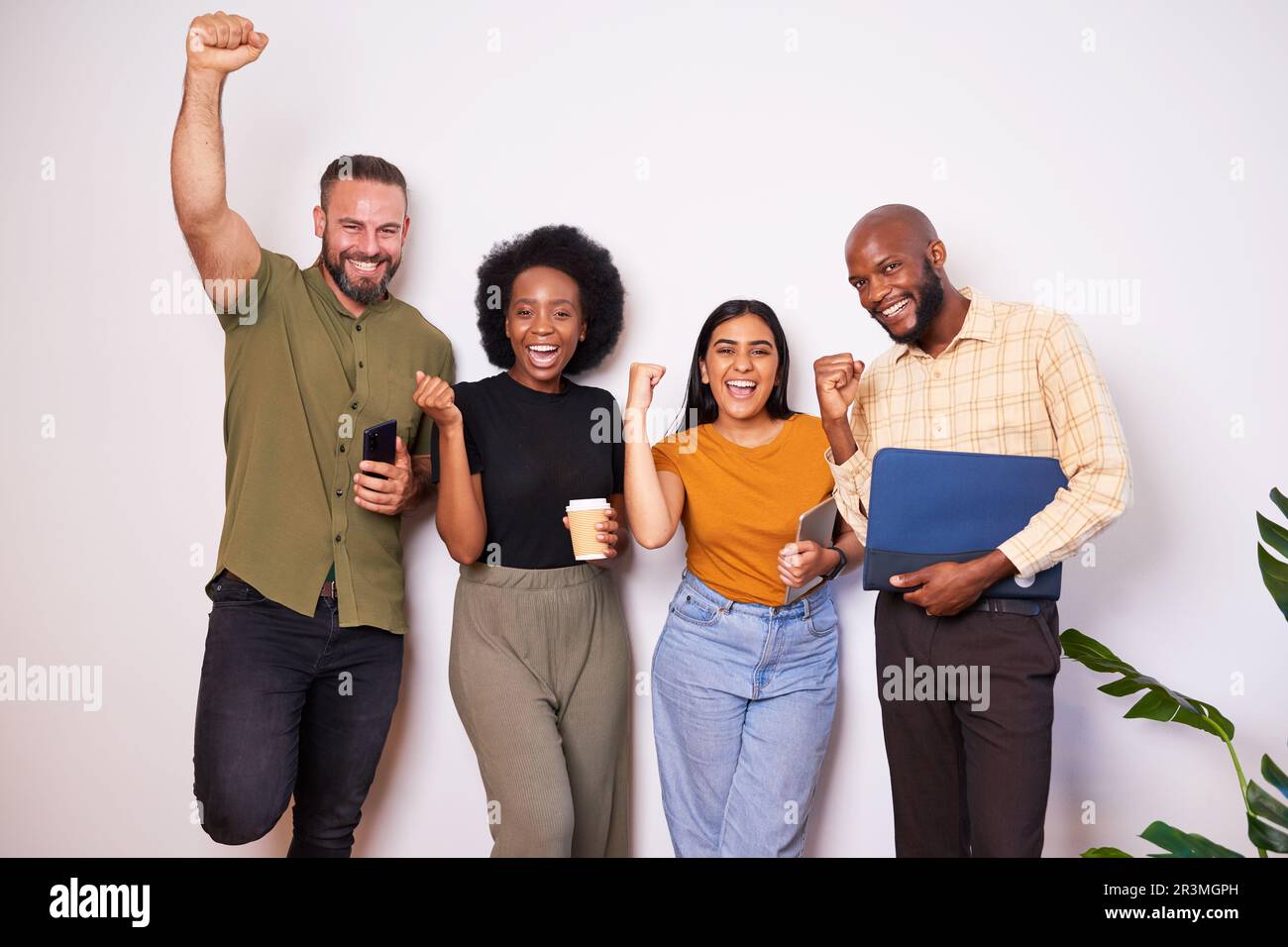 Diverse creative tech team lean against wall and celebrates success ...