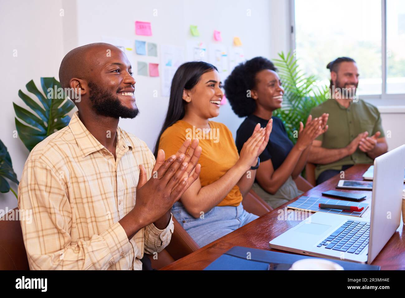 Four diverse team members clapping hands at meeting presentation, tech ...