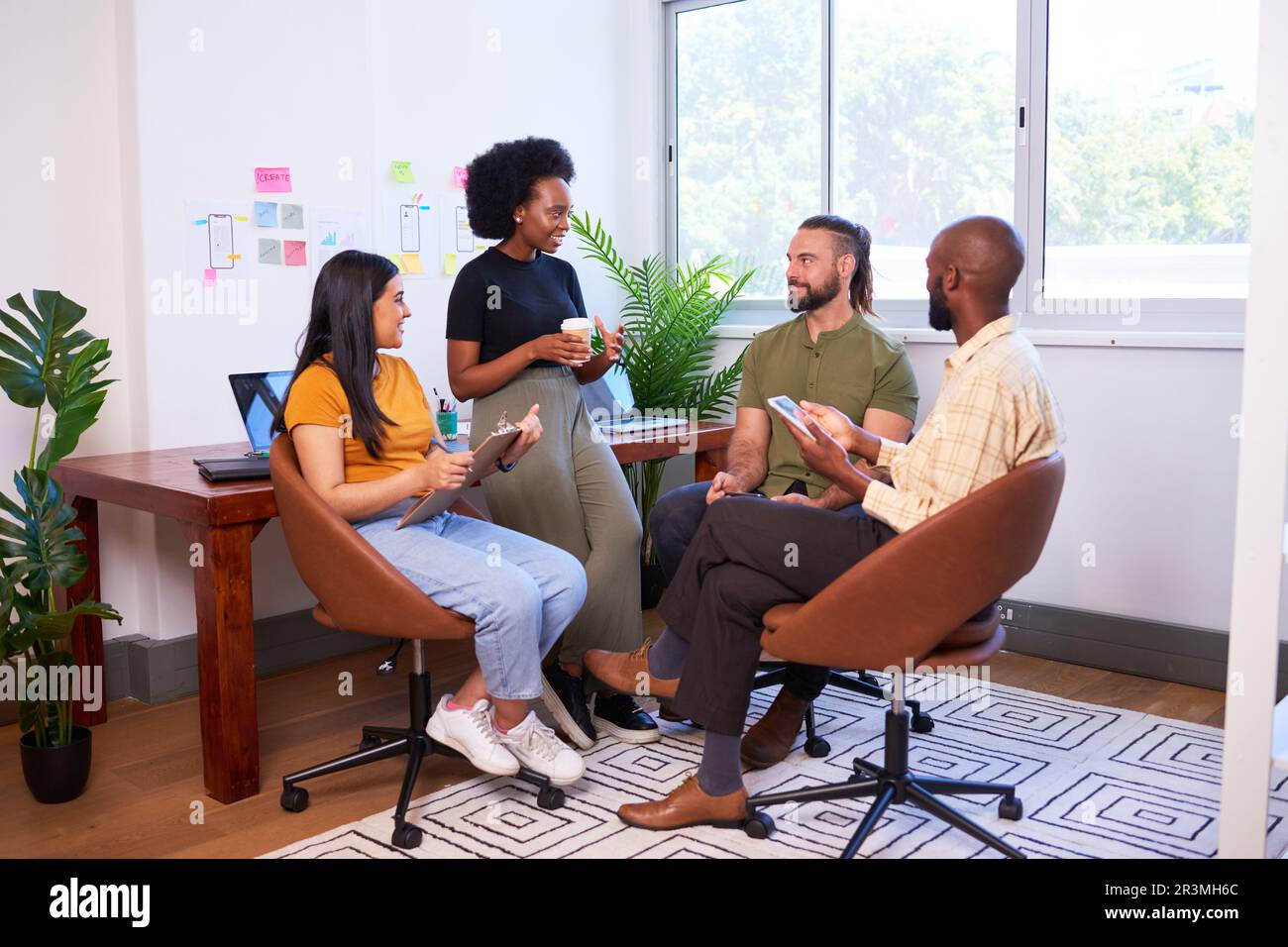 Four diverse team members having informal meeting, sitting in creative ...