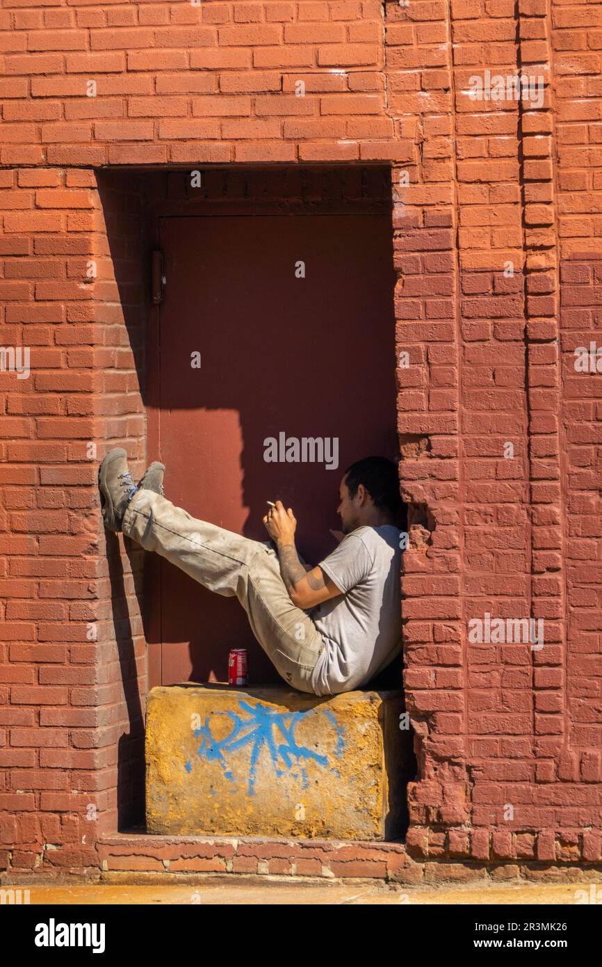 lunch break for a man sitting on a block in a doorway in Brooklyn NYC ...